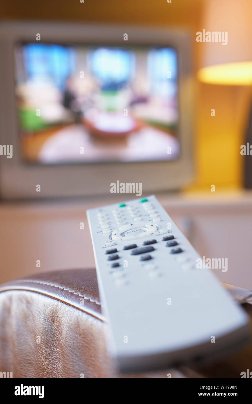 Remote control on leather armchair with television in background Stock ...