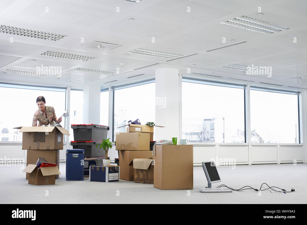 Young businesswoman unpacking cartons in an empty office space Stock ...
