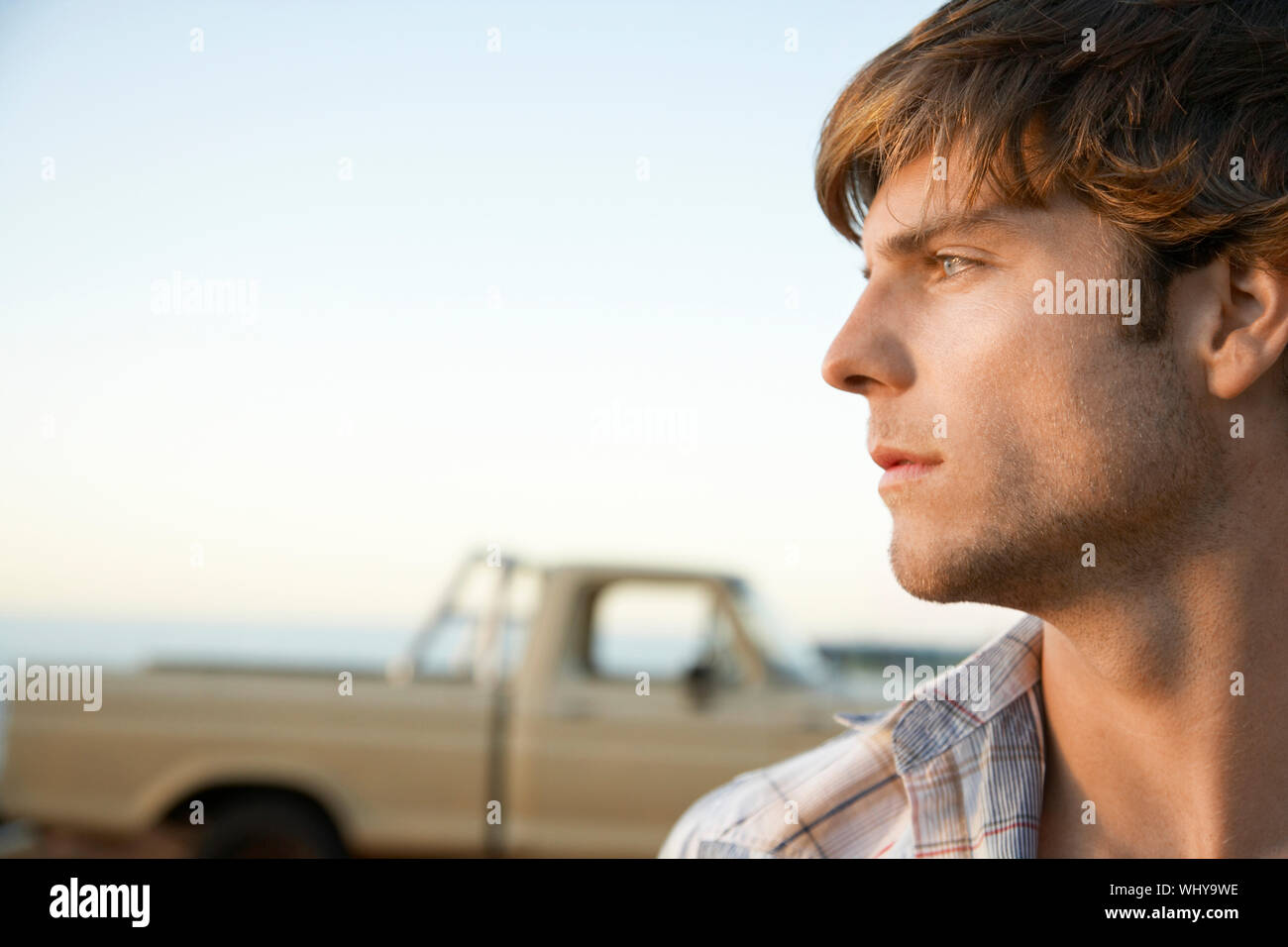 Closeup of thoughtful young man with pick-up truck in background Stock ...