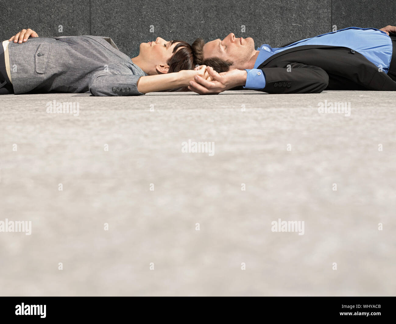 Side view of young businessman and businesswoman holding hands while ...
