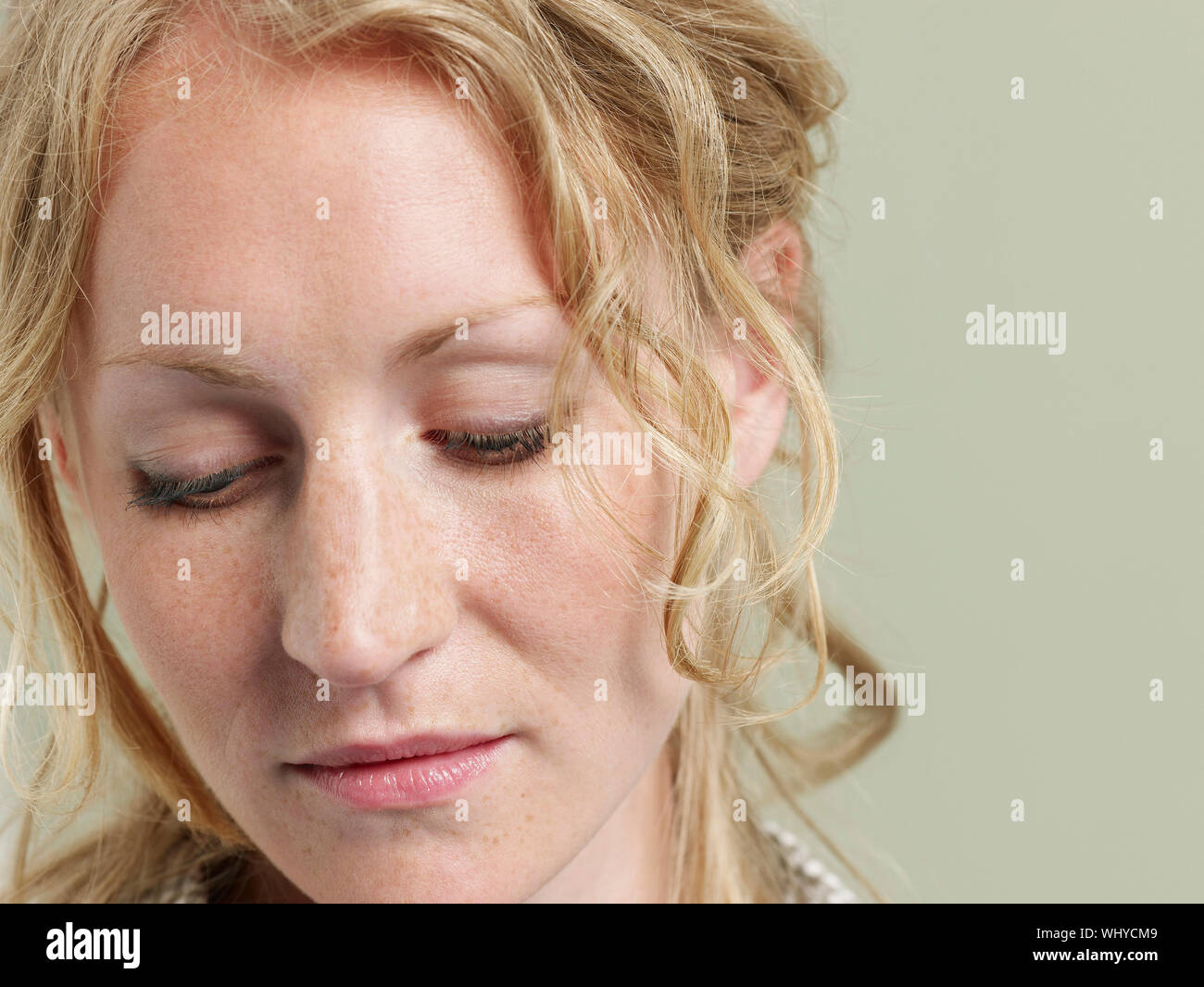 Closeup of sad young woman with wavy hair isolated on colored ...