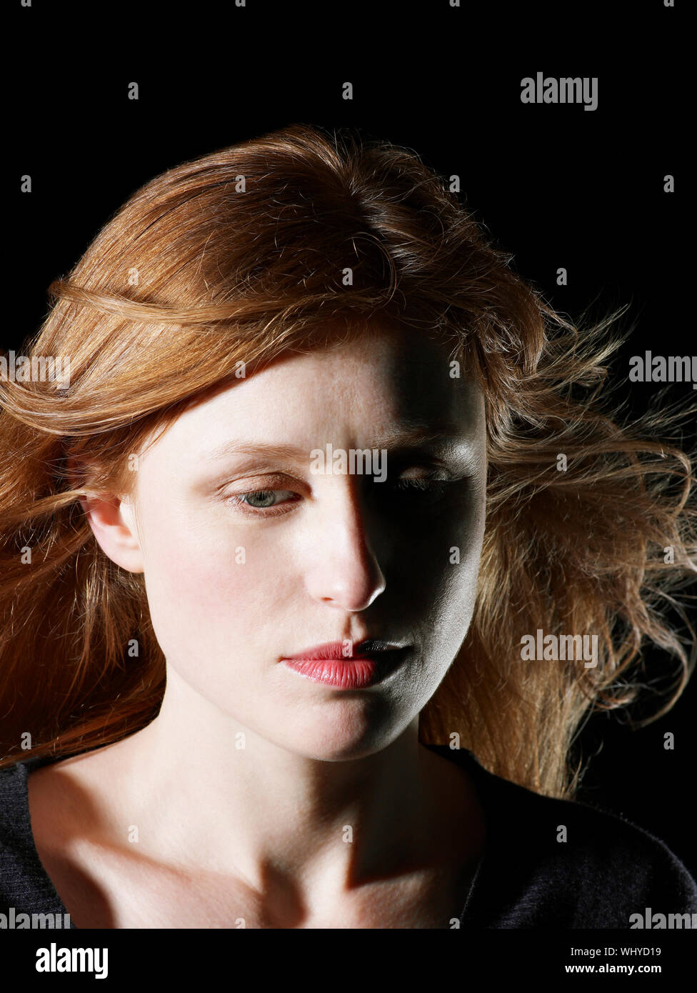 Closeup of beautiful woman with windswept hair looking down on black ...