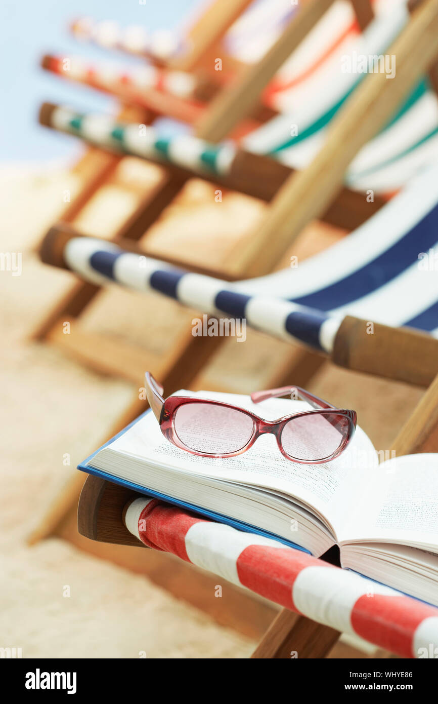 Row of deck chairs on beach book with sunglasses in foreground Stock ...
