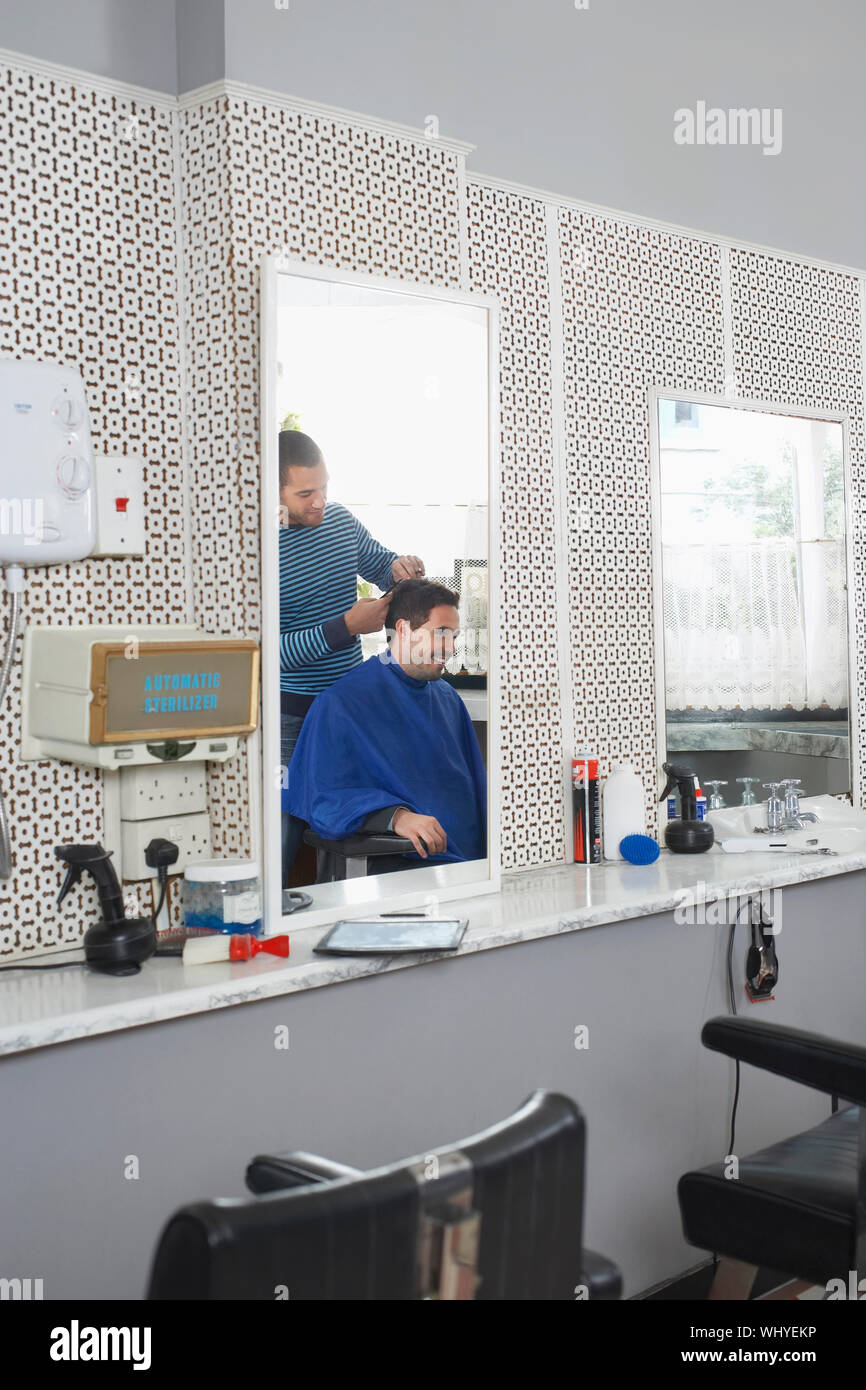Happy businessman getting haircut from hairdresser at salon Stock Photo ...