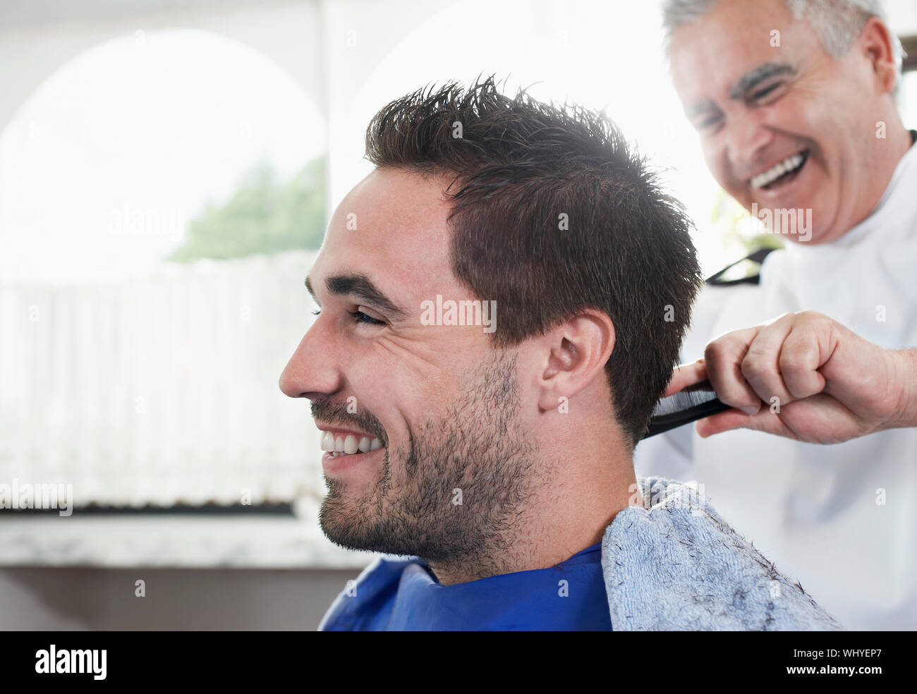 Closeup of happy man getting an haircut from barber in hair salon Stock ...