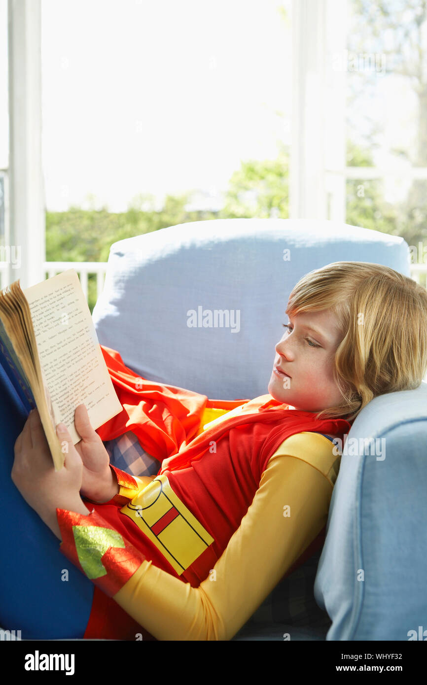 Side view of a young boy in superman costume reading book indoors Stock ...