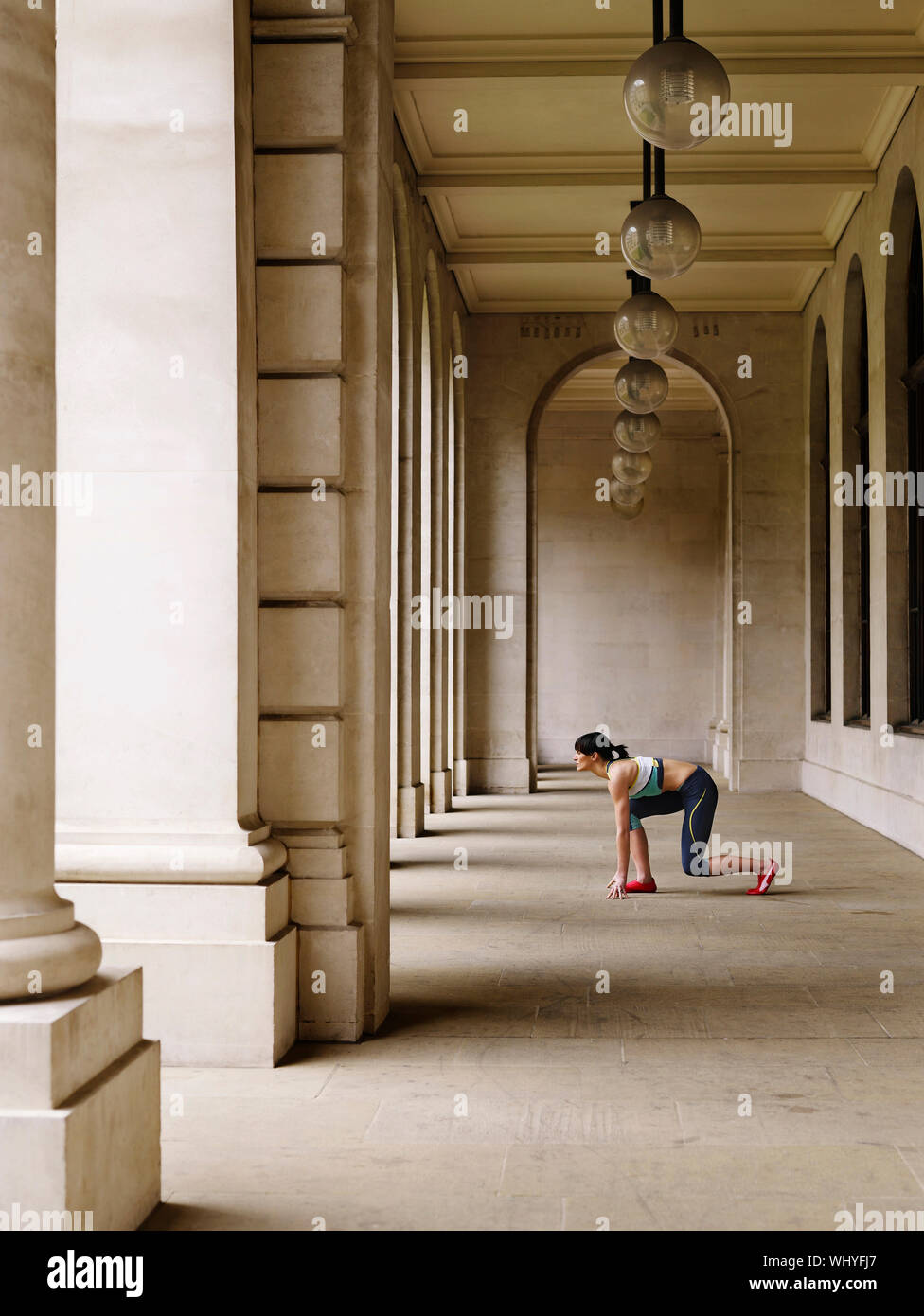 Full length side view of a female runner crouching in starting position ...