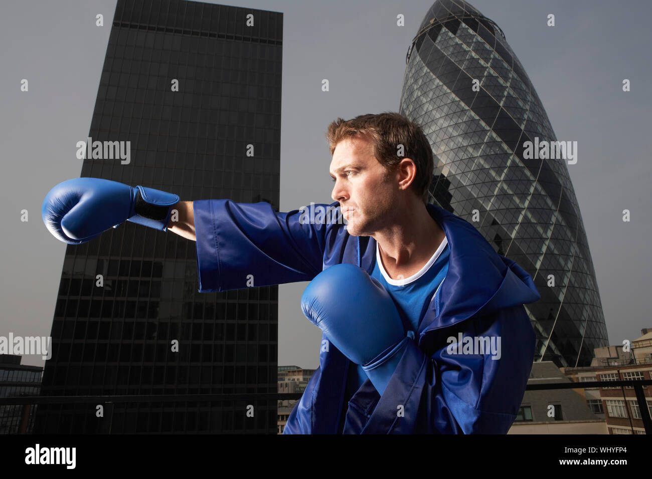 Side view of a male boxer punching air against downtown buildings in ...