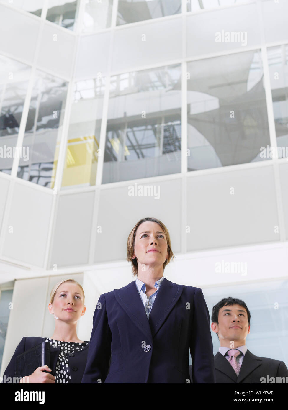 Low angle view of three confidence business people standing in atrium ...