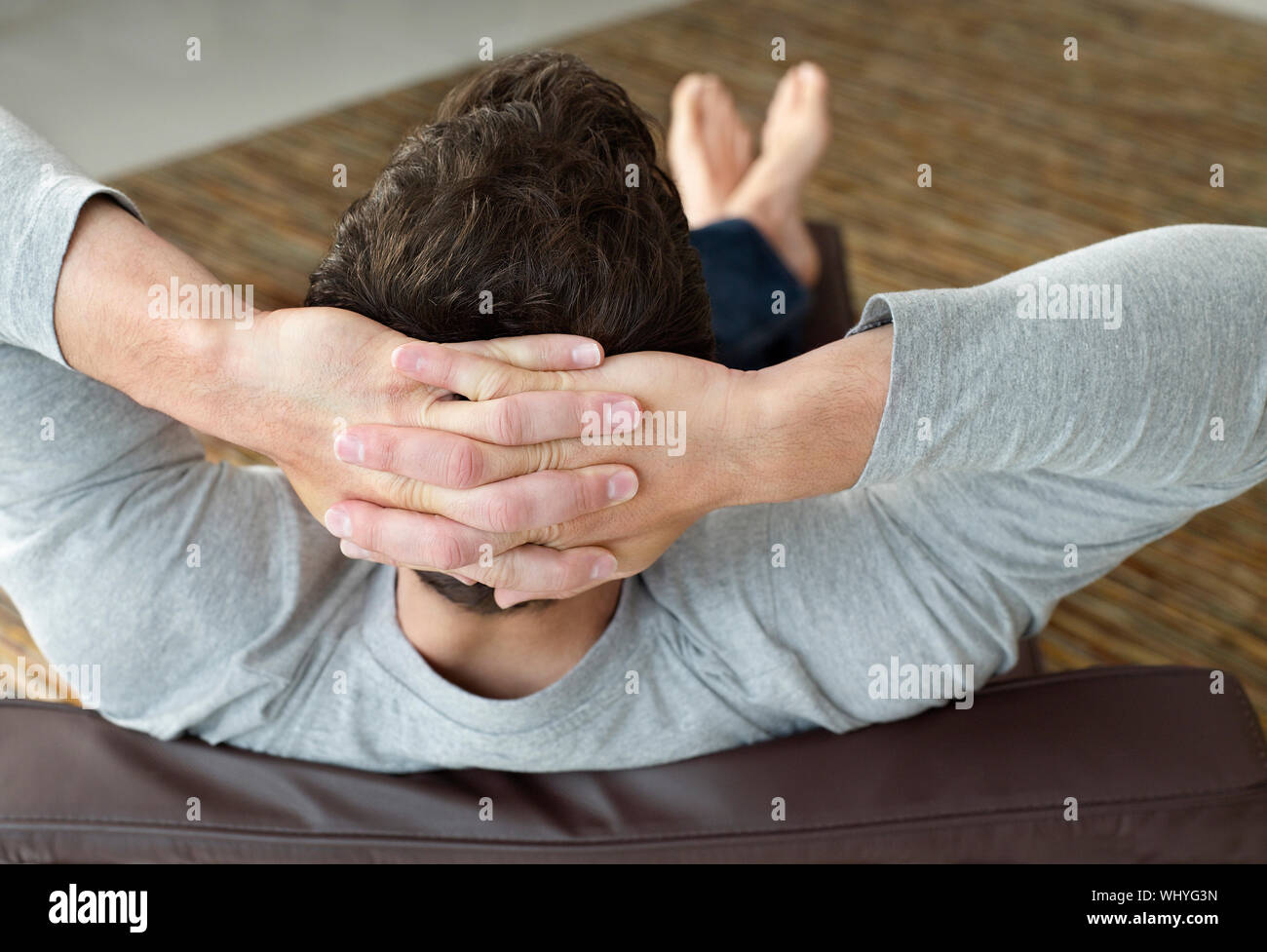 Closeup rear view of a young man sitting with hands behind head Stock ...
