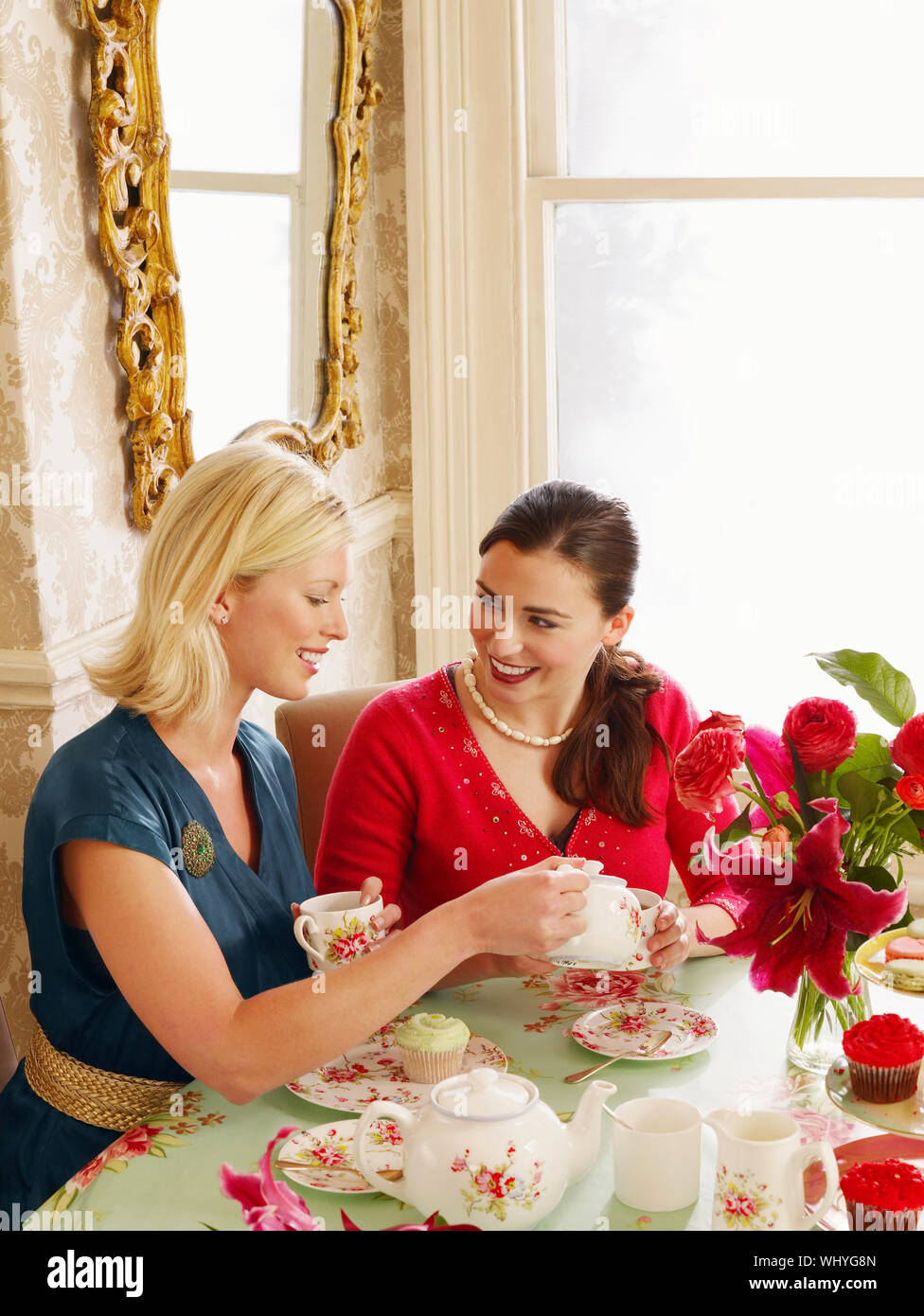 Two young women sitting at dining table to have tea Stock Photo - Alamy