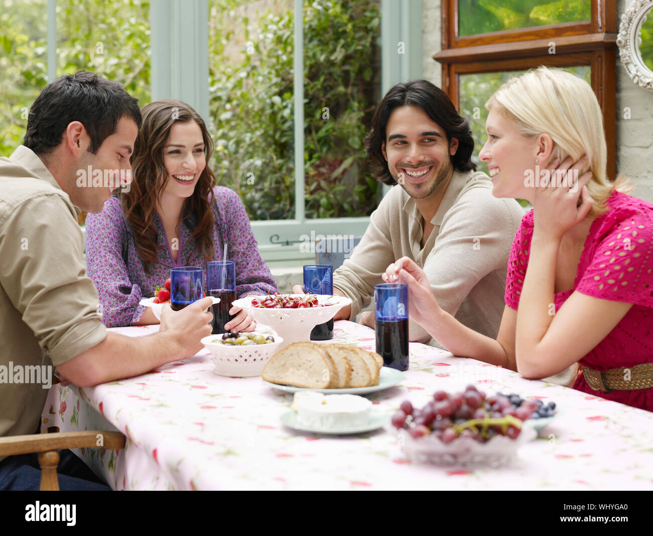 Group of four young people sitting at verandah table Stock Photo - Alamy