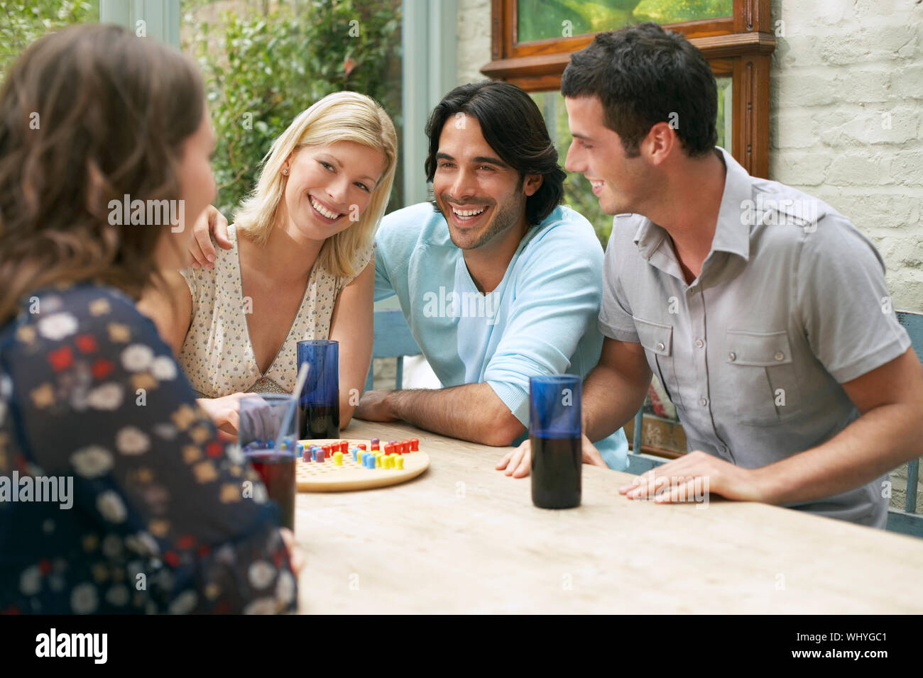 Group of four young people sitting at verandah table Stock Photo - Alamy
