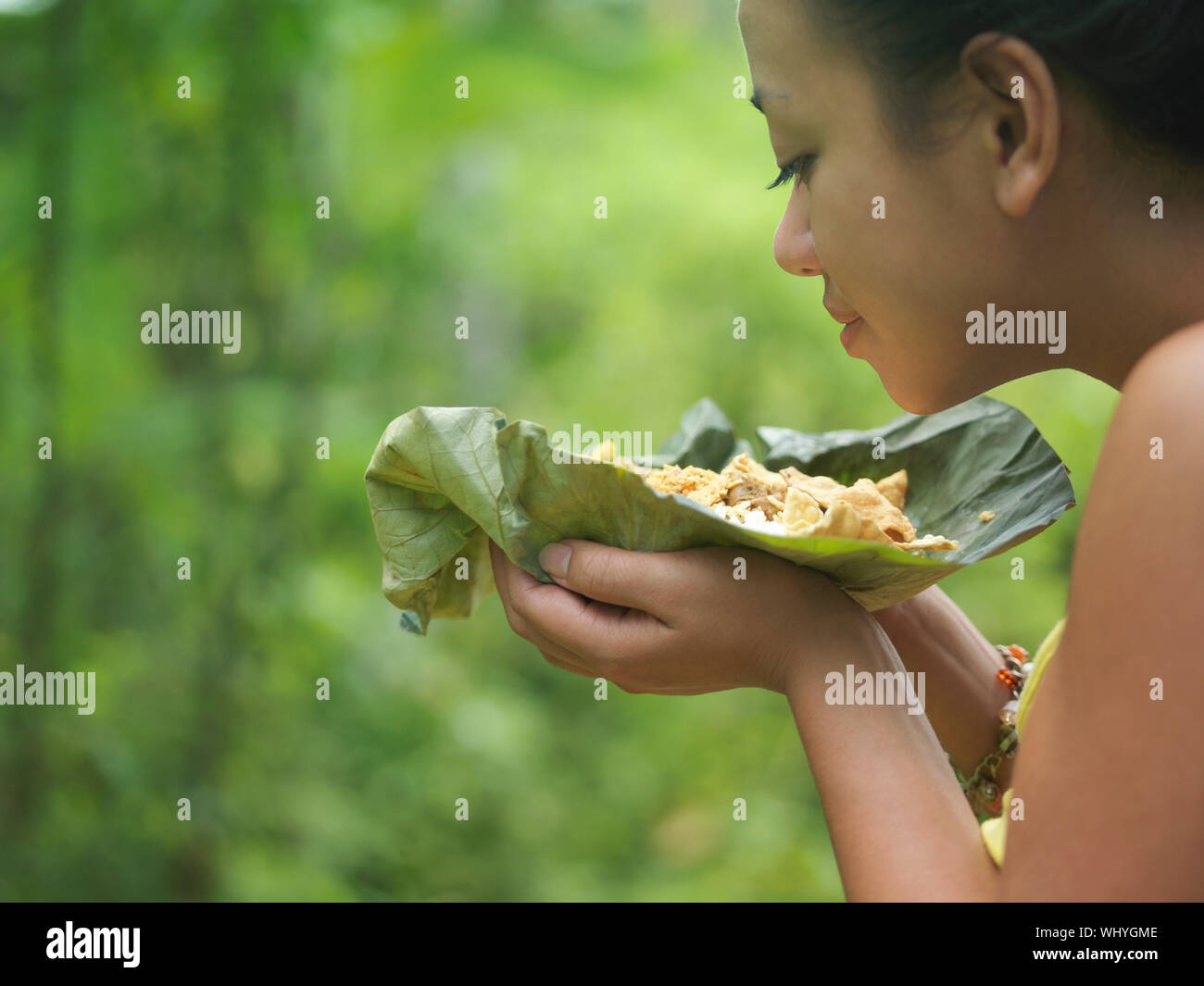 Closeup side view of a young woman smelling food on leaf against ...