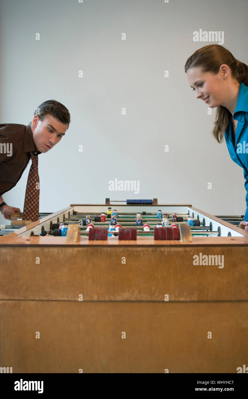 Side view of a young man and woman playing table football in game room ...