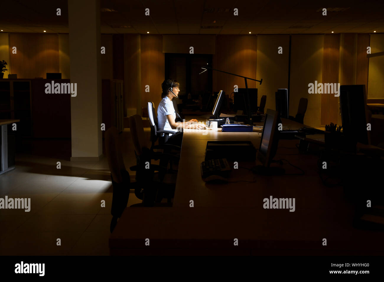 Side view of a young woman working on computer in dark office Stock ...