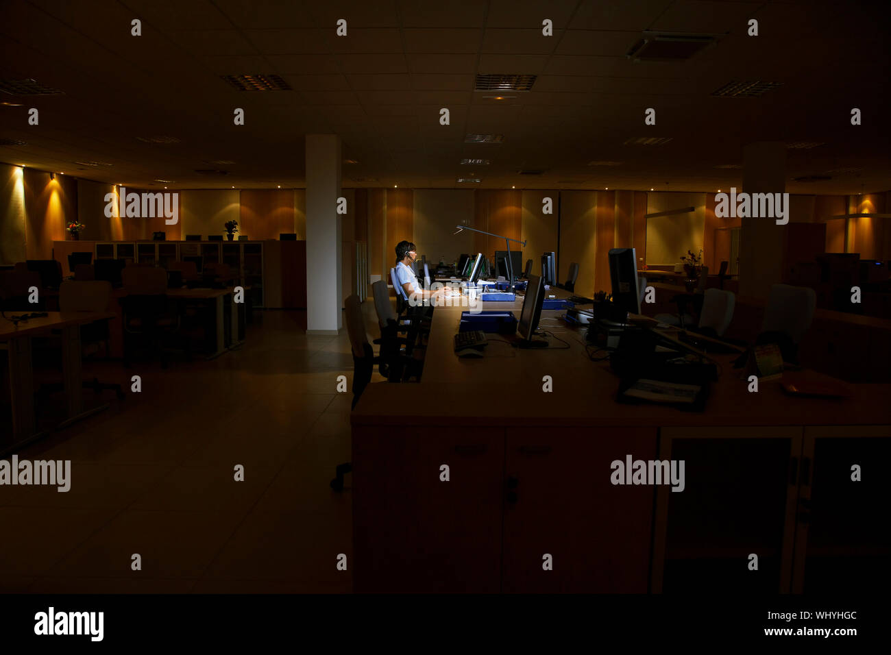 Side view of a young woman working on computer in dark office Stock ...
