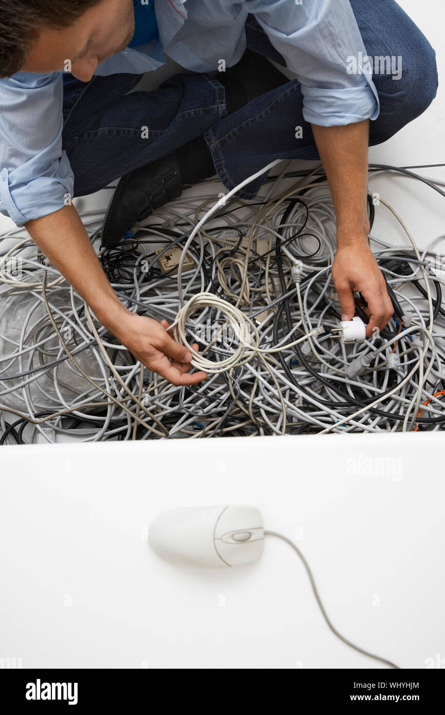 Elevated view of a cropped man working on tangled computer wires in ...