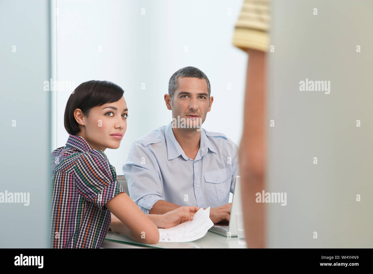 Two office workers looking up at cropped coworker standing in doorway ...