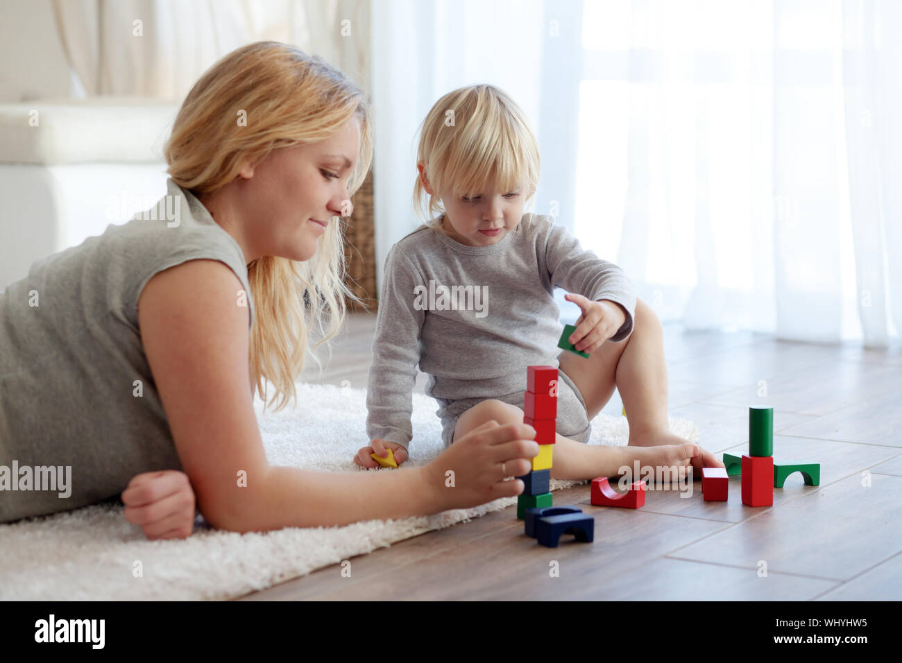 Mother with a child playing with wooden blocks at home Stock Photo - Alamy