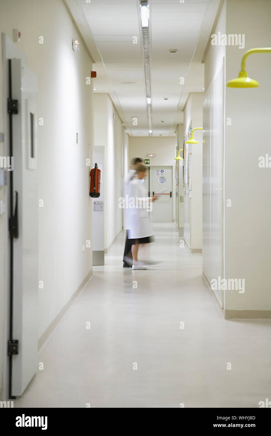 Full length side view of male and female scientists walking down ...