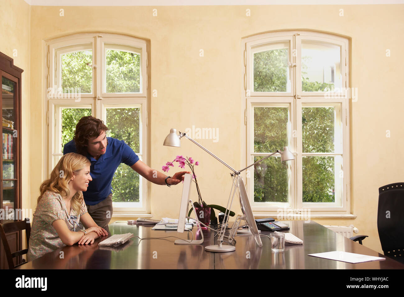 Side view of a man helping young woman work on computer in study room ...