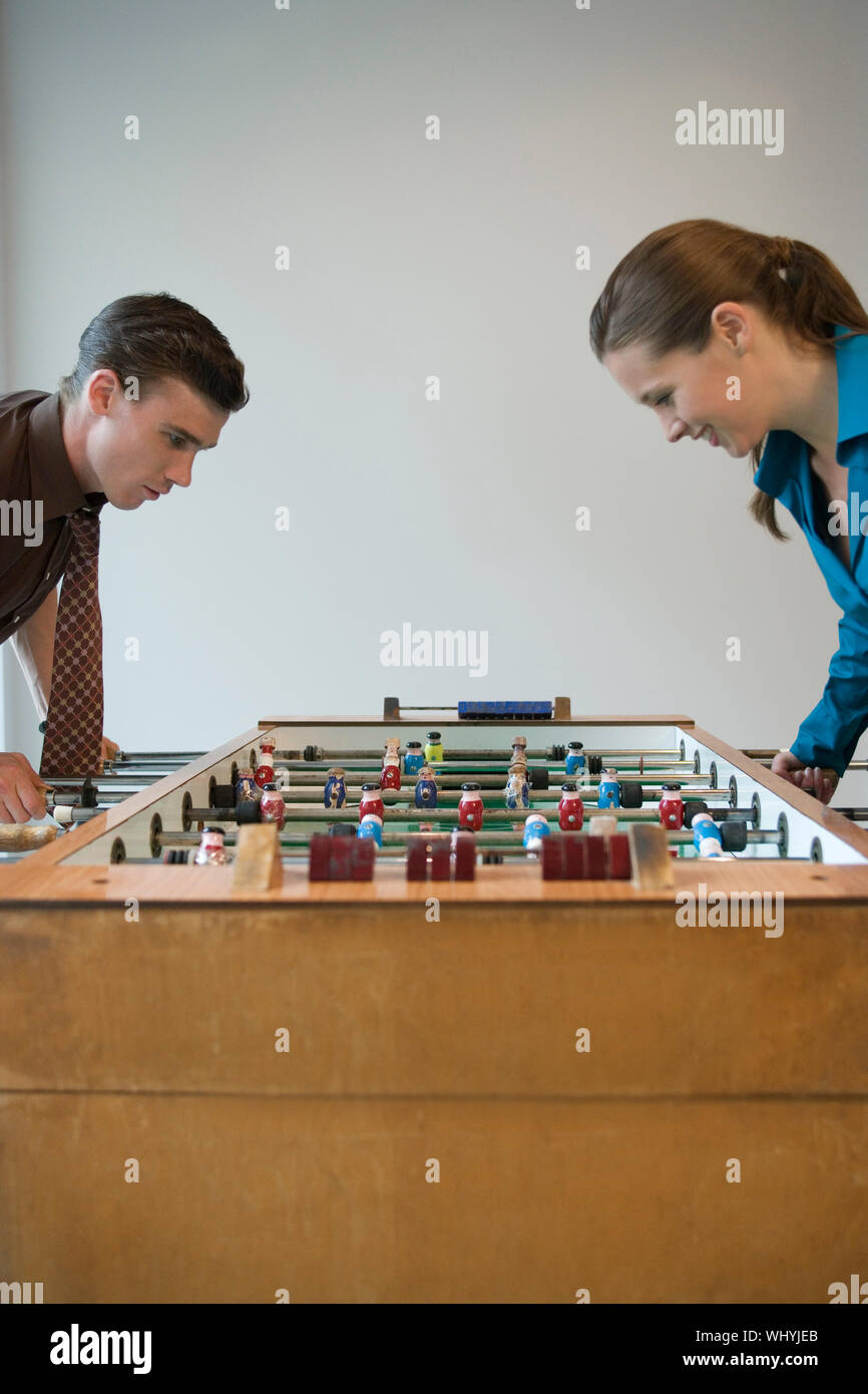 Side view of a young man and woman playing table football in game room ...