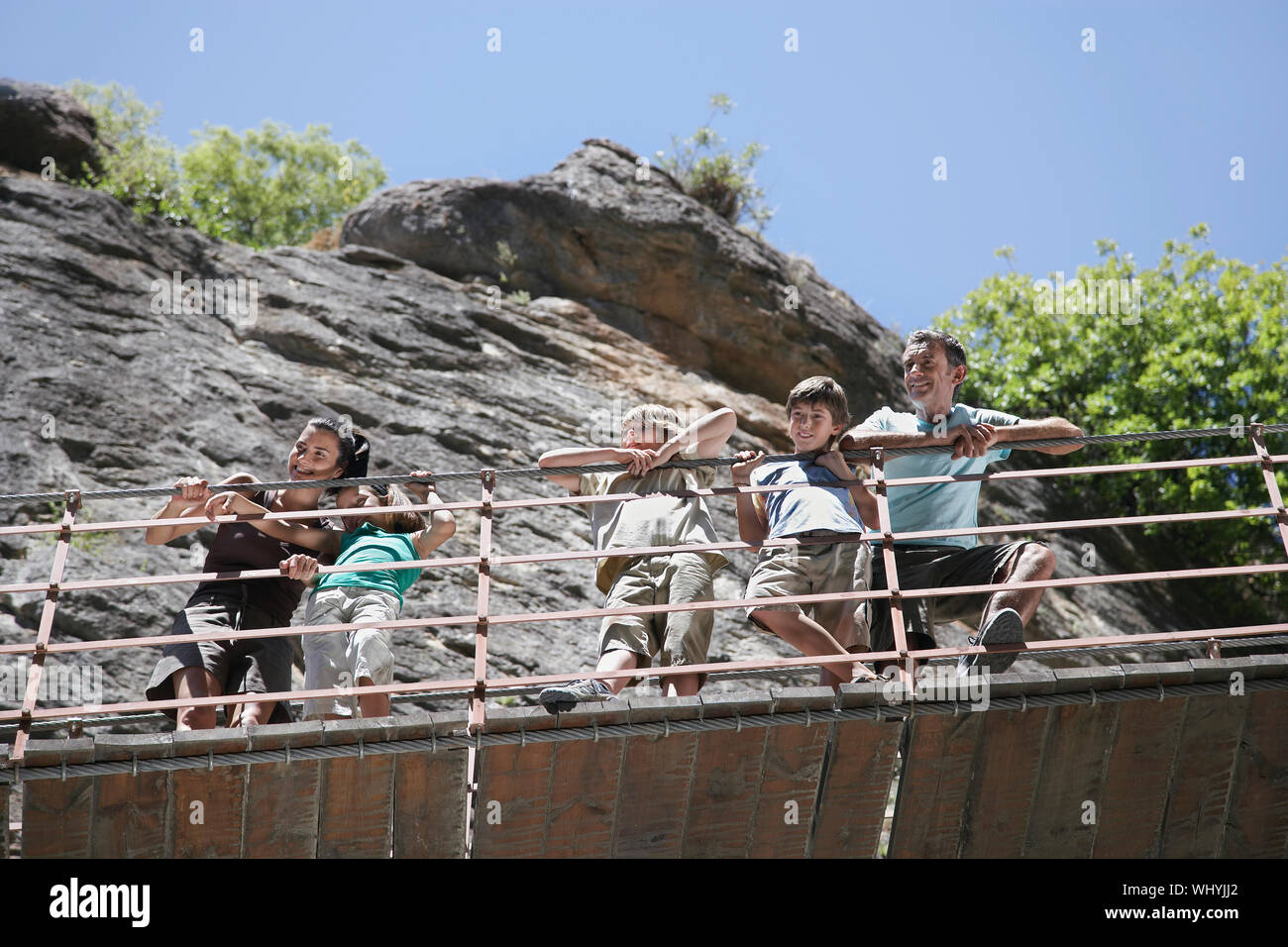 Low angle view of a couple with three children looking down from bridge ...