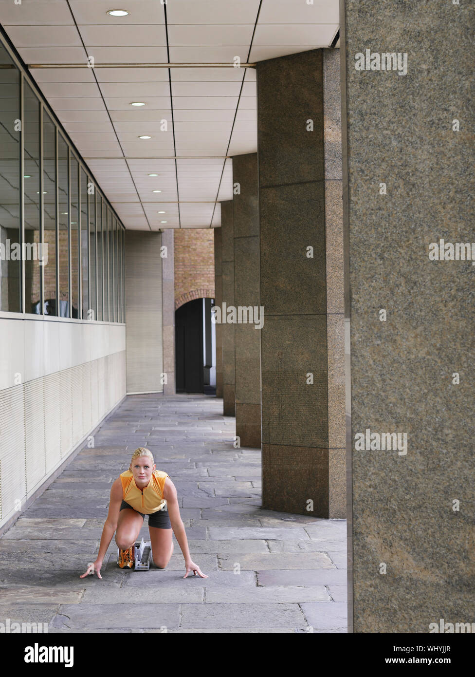 Full length of a female athlete crouching in starting position on ...
