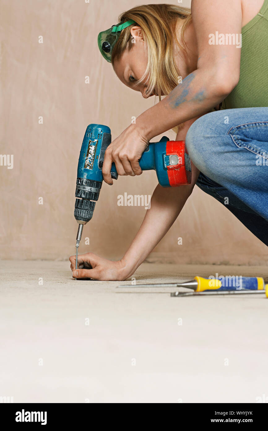 Side view of a casual cropped young woman drilling floor Stock Photo ...