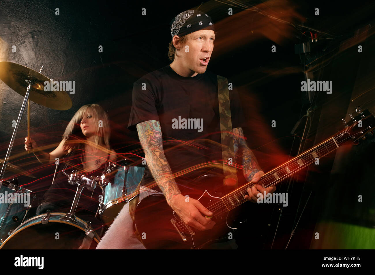 Band playing on a stage. Female drummer and male guitarist. Shot with ...