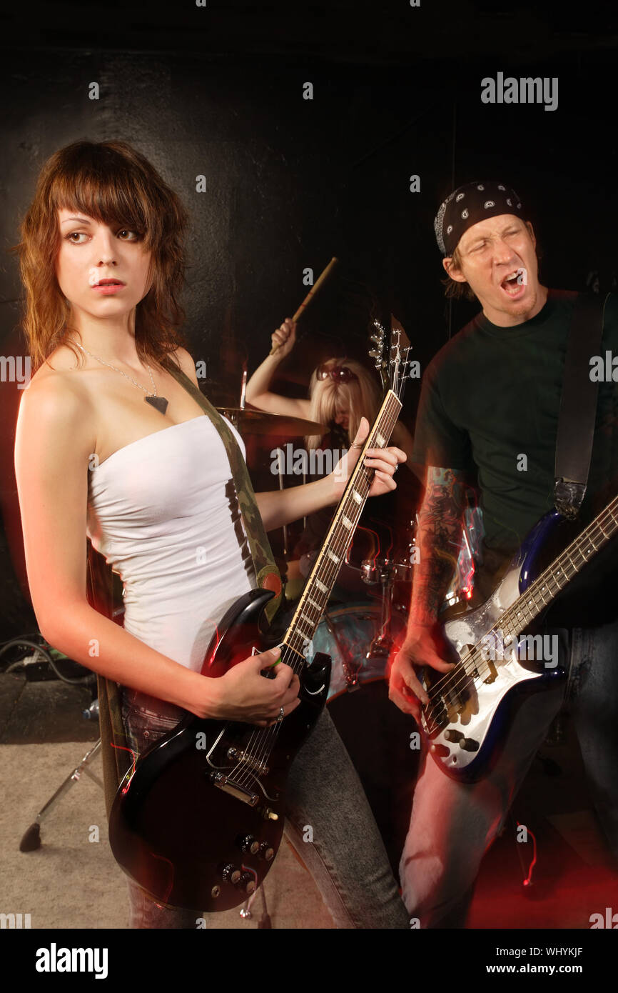 Band playing on a stage. Female guitarist, male bassist and female ...