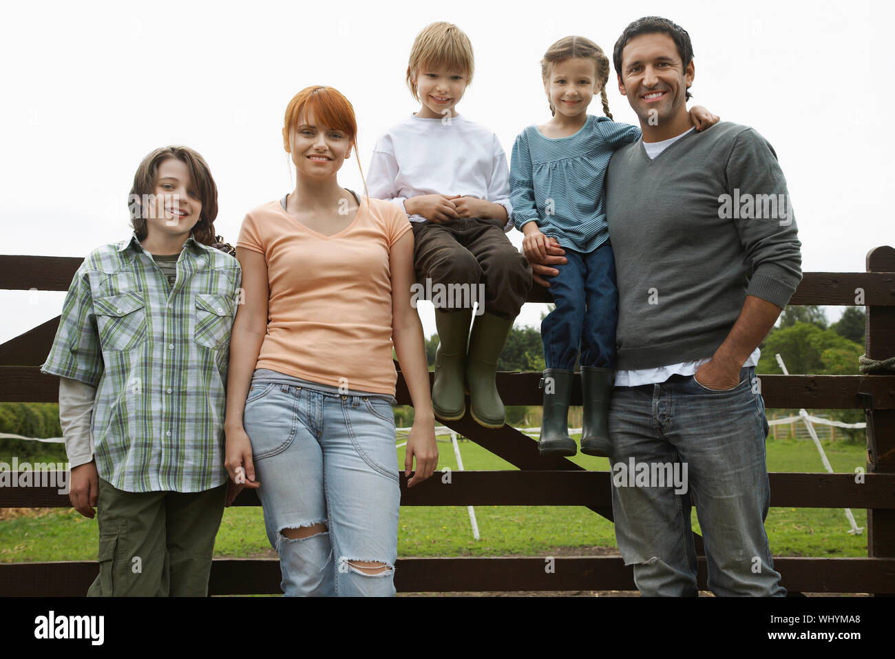 Parents with three children standing against fence in the field Stock ...