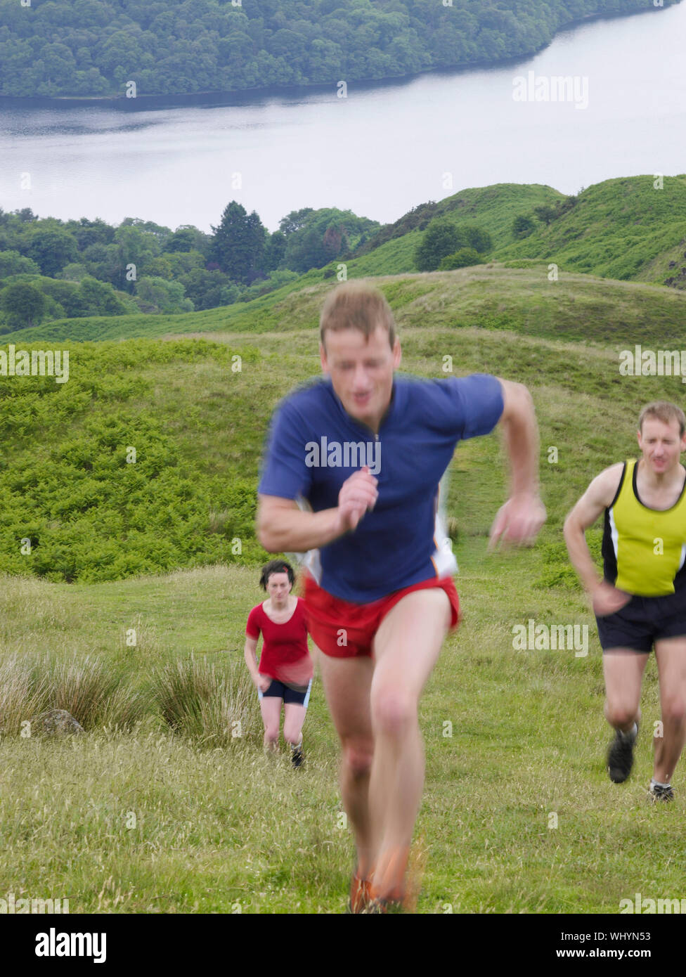 Three people running up country hill Stock Photo - Alamy
