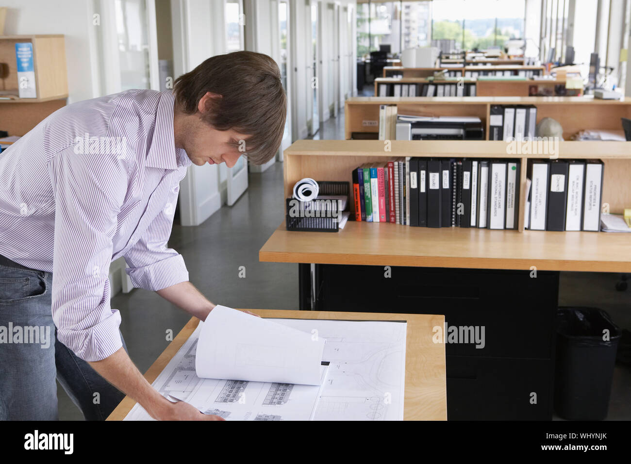 Side view of a young male architect studying blueprint in office Stock ...