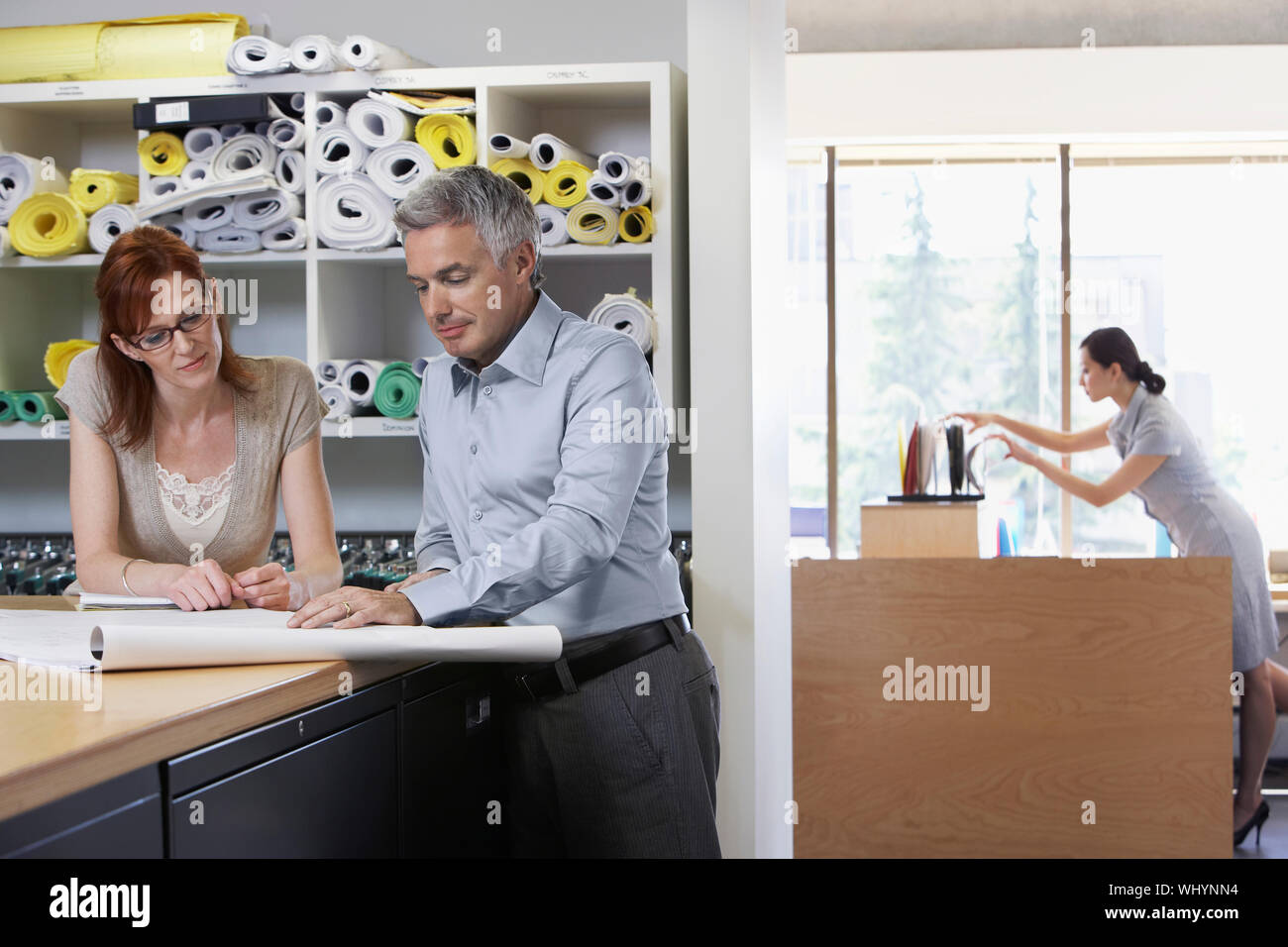 Businessman and woman studying paperwork in office Stock Photo - Alamy