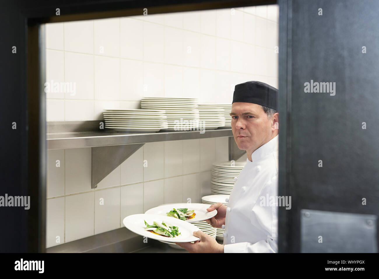 Portrait of a male chef holding food plates in the kitchen Stock Photo ...