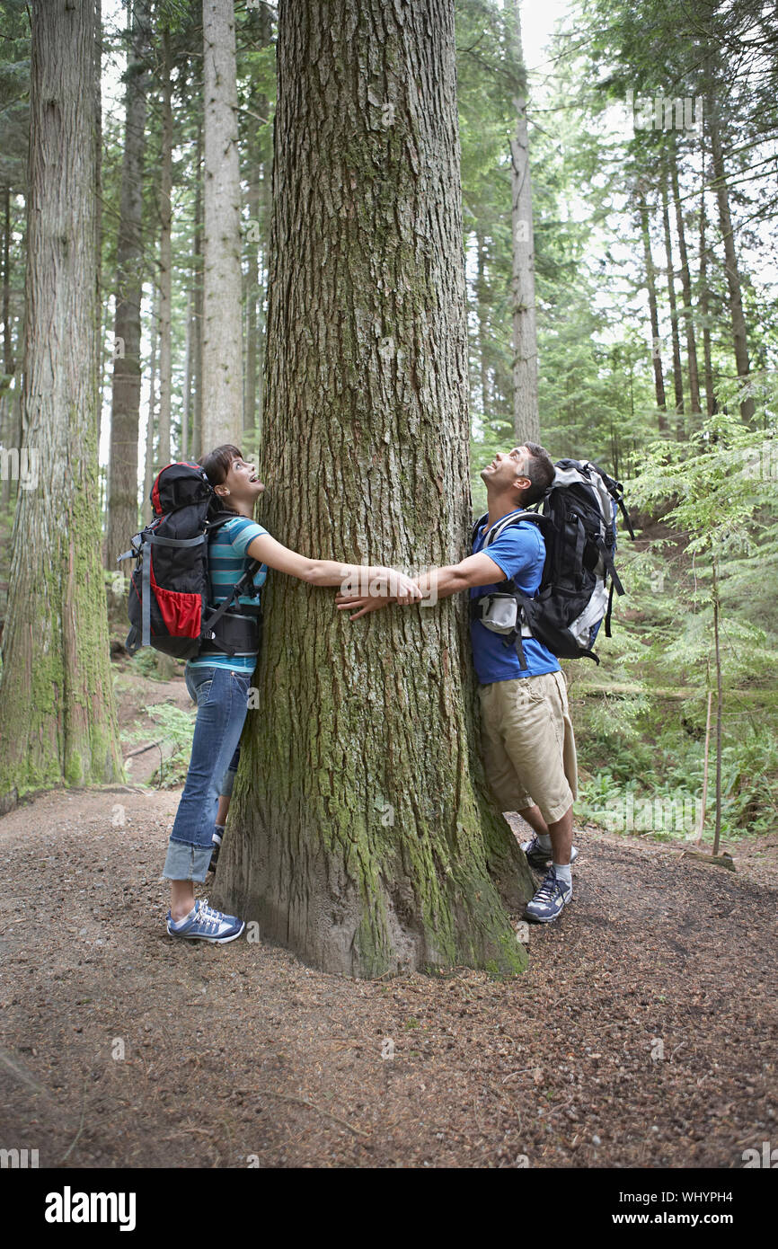 Full length side view of a young couple hugging tree in forest Stock ...