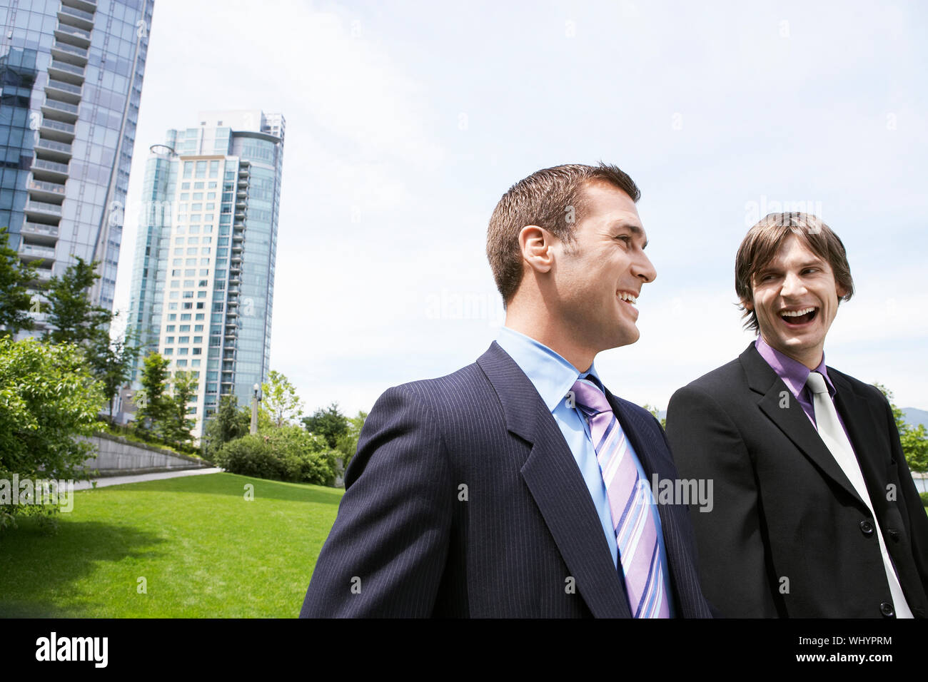 Two cheerful young businessmen laughing near office buildings Stock ...