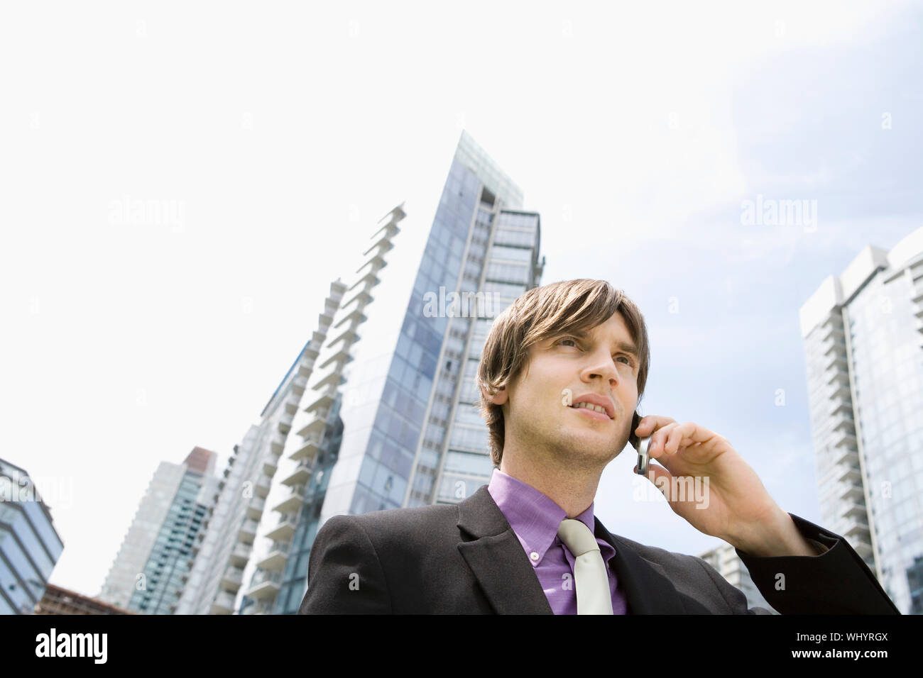 Young businessman using mobile phone outside office buildings Stock ...