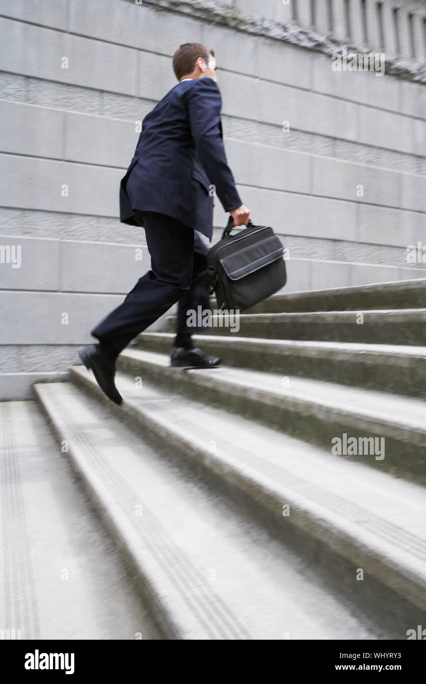 Full length side view of a businessman with briefcase ascending steps ...
