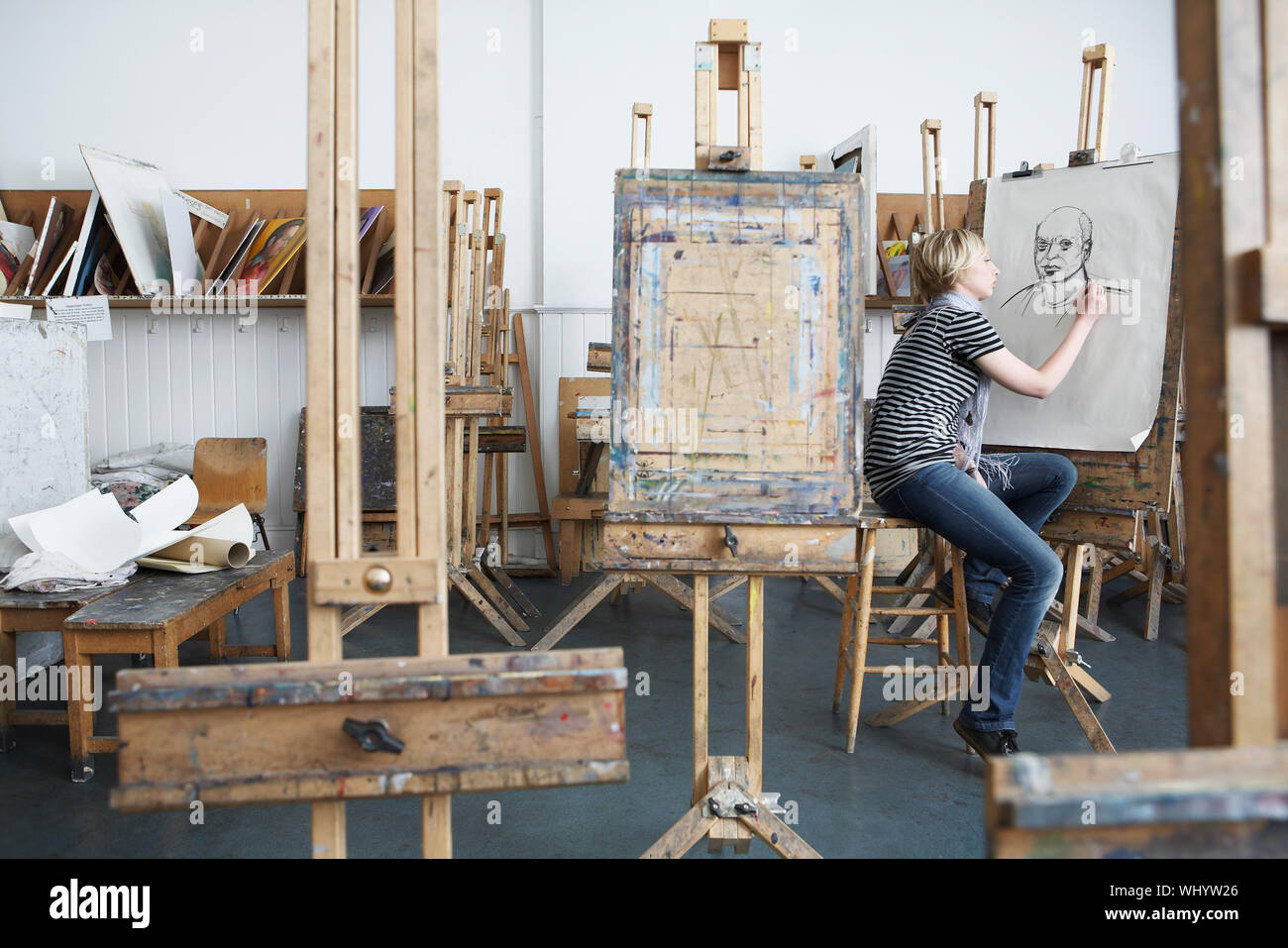 Full length side view of a young female student drawing charcoal ...