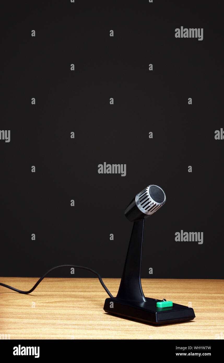 Old fashioned microphone on desk, black background Stock Photo - Alamy