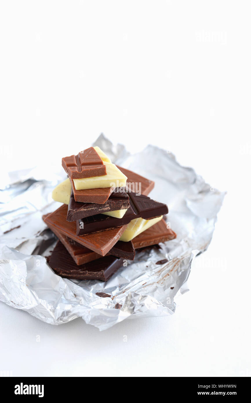 Stack of different chocolate pieces on aluminum foil, studio shot Stock ...