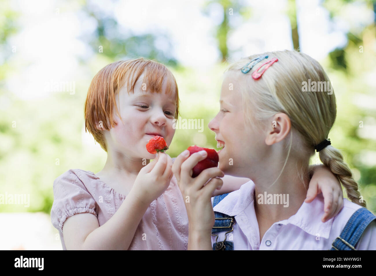 Closeup of two smiling young girls eating fruits outdoors Stock Photo ...