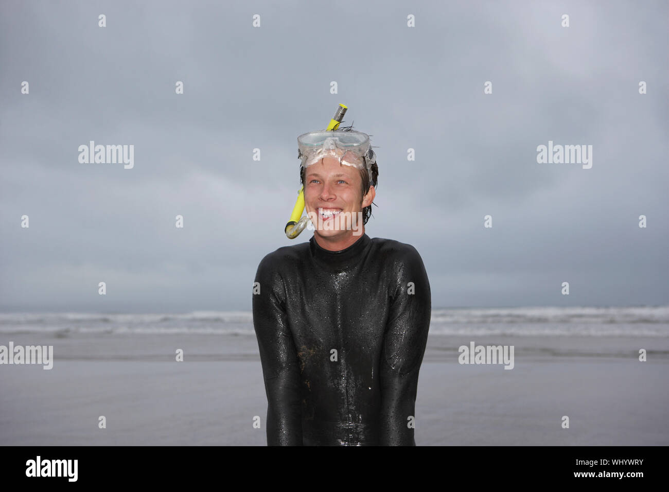 Male surfer wearing goggles and mask standing in water at beach Stock ...