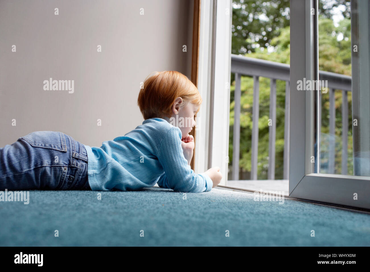 Side view of little girl looking out through balcony while lying on ...