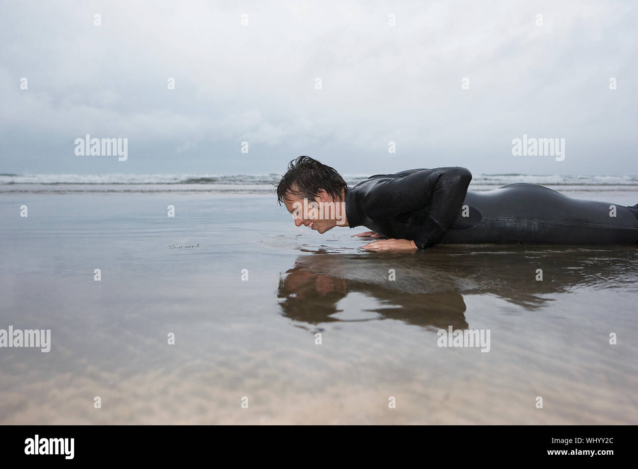 Side view of young male surfer lying in water at beach Stock Photo - Alamy