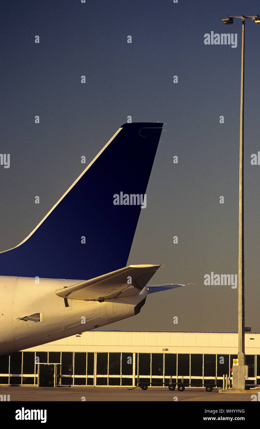 Passenger jet tailplane against airport terminal Stock Photo - Alamy