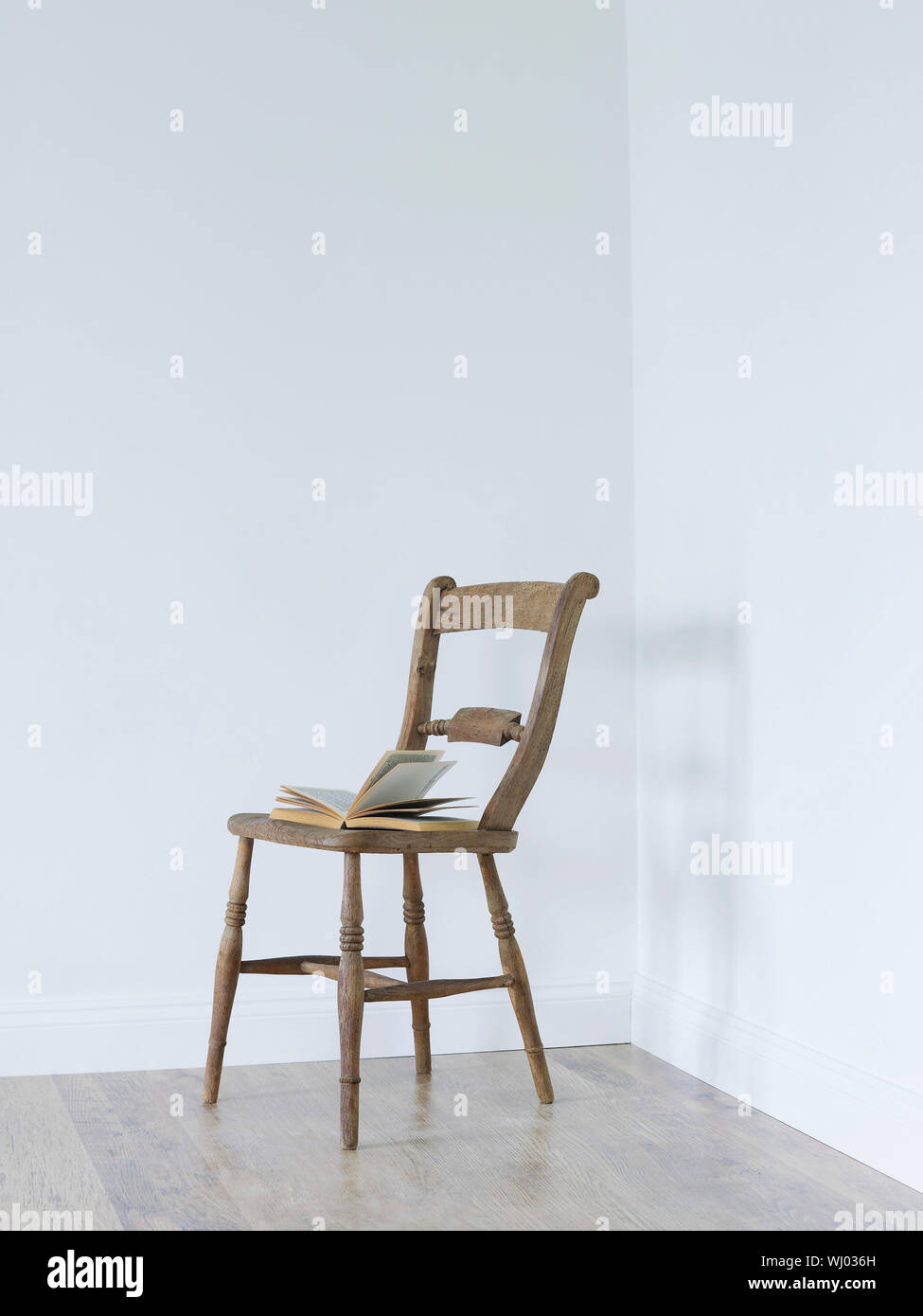 Open book on chair in empty room corner Stock Photo - Alamy